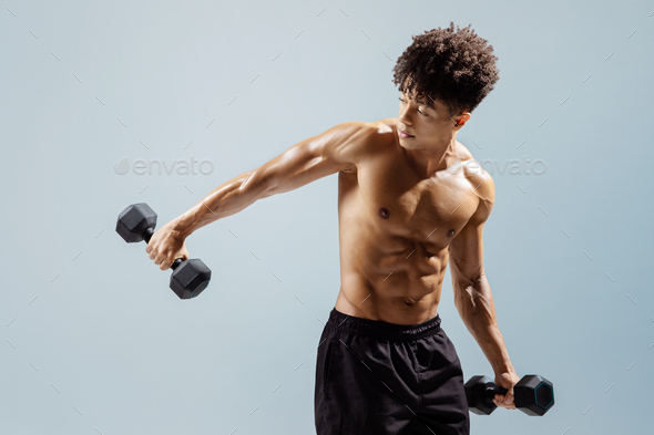guy exercising with dumbbells shirtless strengthening arms over gray ...