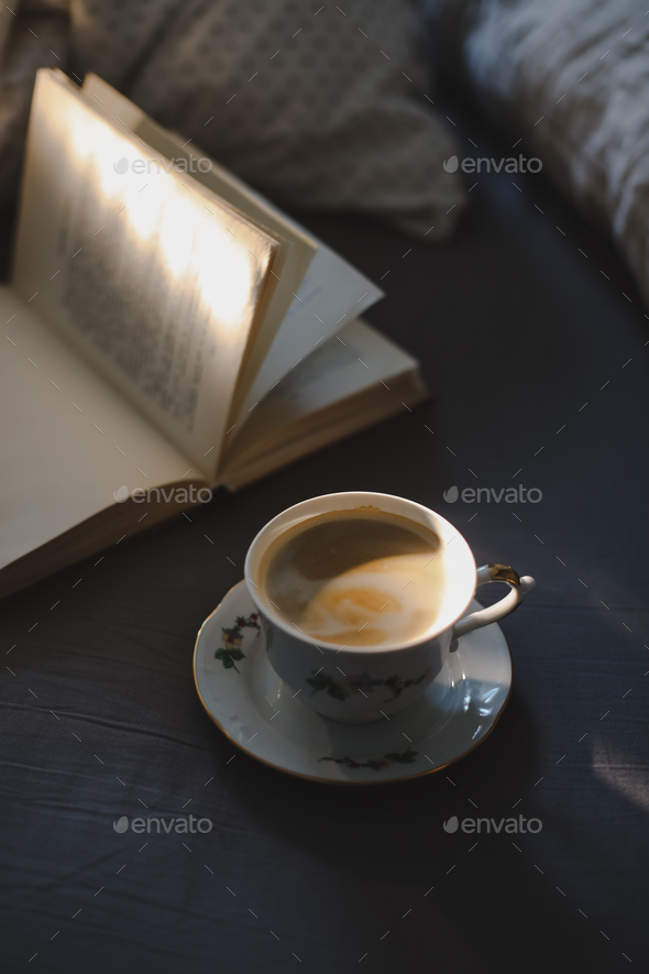 a cup of coffeeand a book in bed. Coffee in a cozy interior home ...