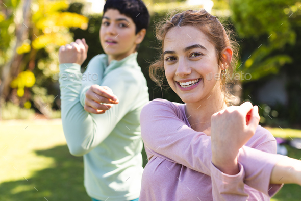 Happy Biracial Lesbian Couple Practicing Yoga Standing And Stretching
