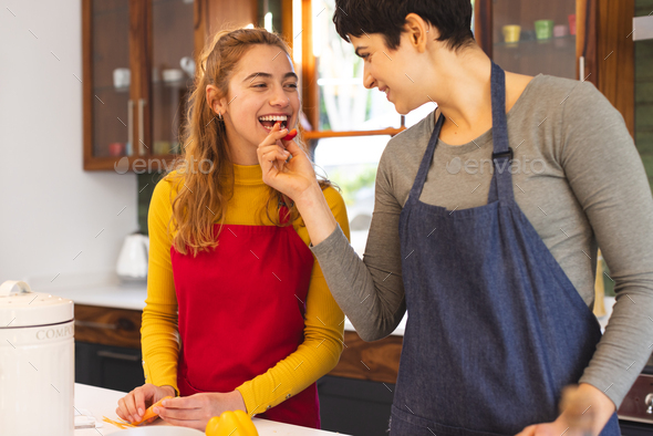 Happy Biracial Lesbian Couple Preparing And Tasting Vegetables In