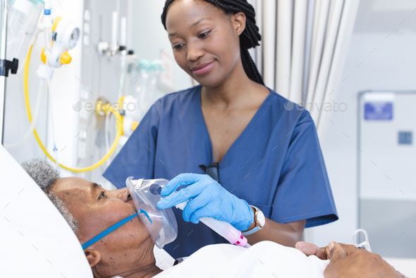 African american female doctor applying oxygen mask to senior female ...