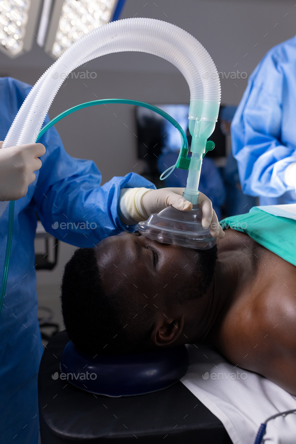 Asian female doctor with face mask holding oxygen mask on patient face ...