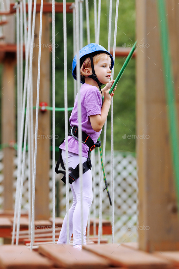 Child on ropes course with helmet and harness Stock Photo by kaplickaya