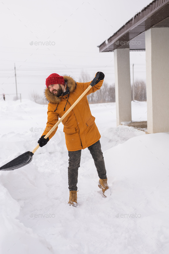 Young man clearing snow in his backyard village house with shovel ...