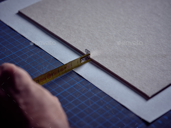 Crop bookbinder measuring paper with tape at table during work Stock ...