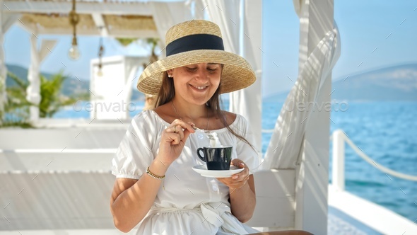 Young brunette woman relaxing at the sea beach cafe or restaurant and ...