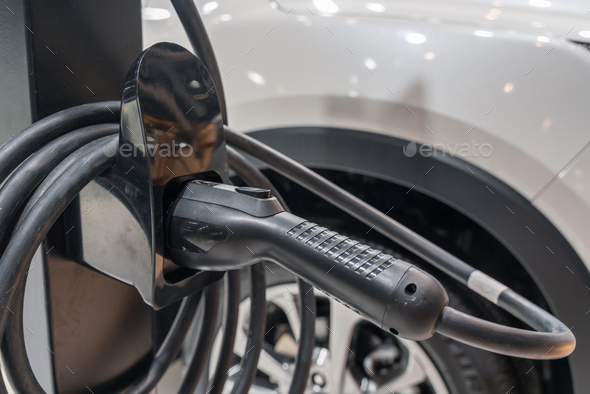 close up view of electric car charger with blurred car background ...