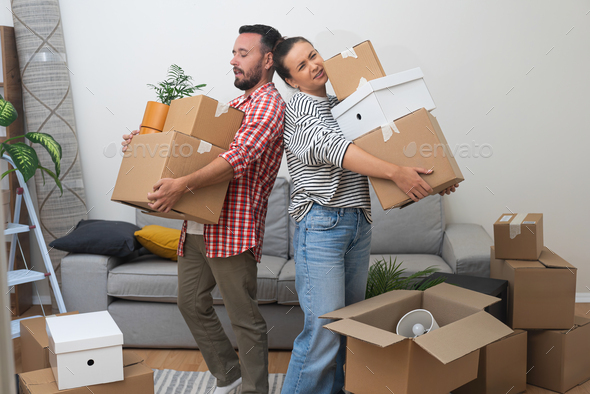 Overstressed man and woman hold heavy boxes with goods Stock Photo by ...