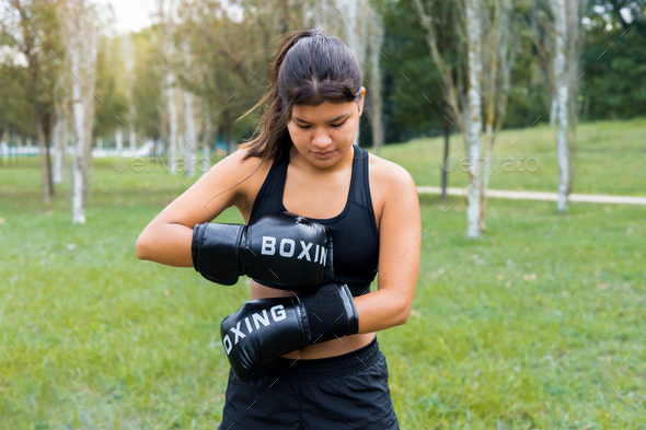 Boxer woman putting on boxing gloves in an outdoor sparring training ...