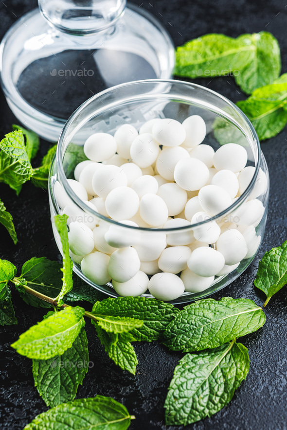 Mint candies in jar. Menthol bonbons and mint leaves on black table ...