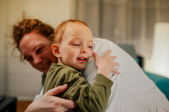 A happy child is hugging his friendly pediatrician during her visit at ...