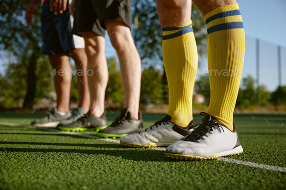 Football player legs standing on white line dividing football field ...