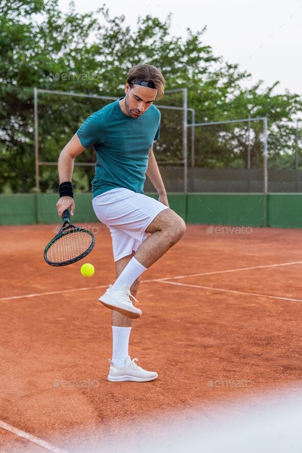 Caucasian young man picking up the ball from the ground with the ...