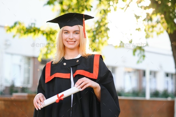 Portrait enthusiastic female college student graduate in cap and gown ...