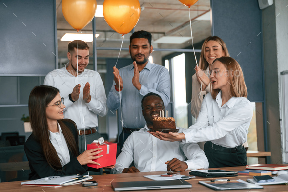 man with sweet cake with candles. Employee having a birthday in the ...