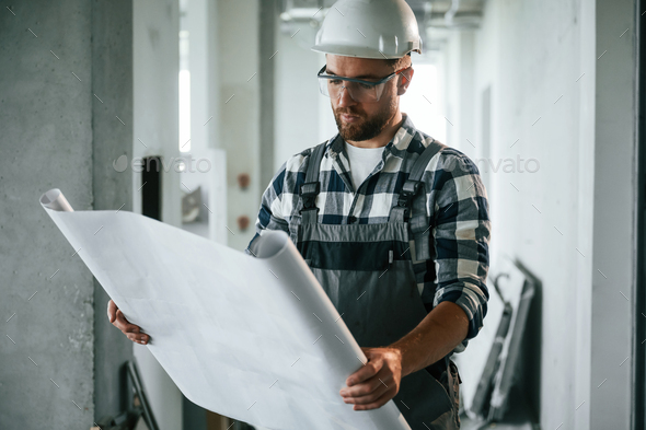 Project on the paper, holding in hands. Construction worker in uniform ...