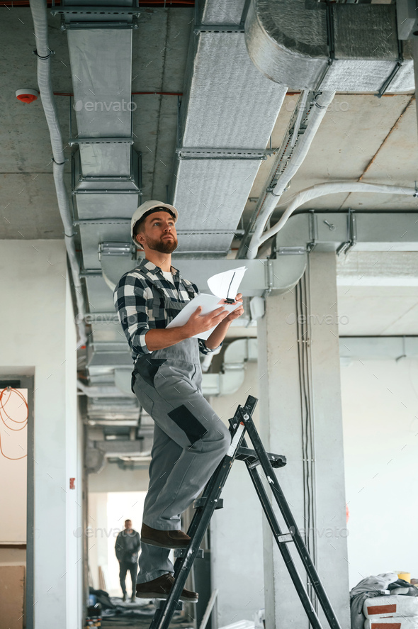 Checking the ceiling. Construction worker in uniform in empty ...