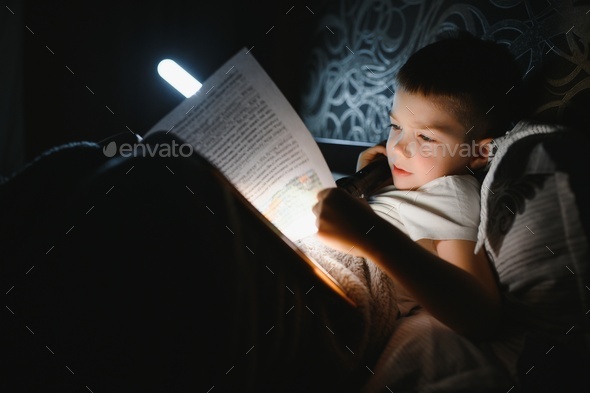 Child reading book in bed. Kids read at night. Little boy with fairy ...