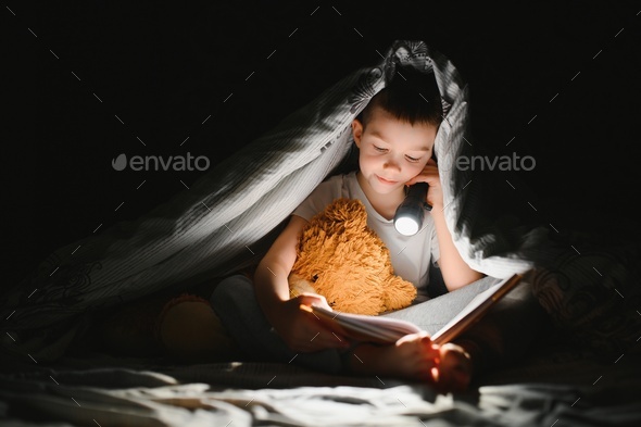 Child reading book in bed. Kids read at night. Little boy with fairy ...