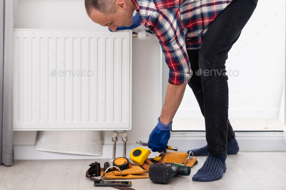 Repair heating radiator close-up. man repairing radiator with wrench ...