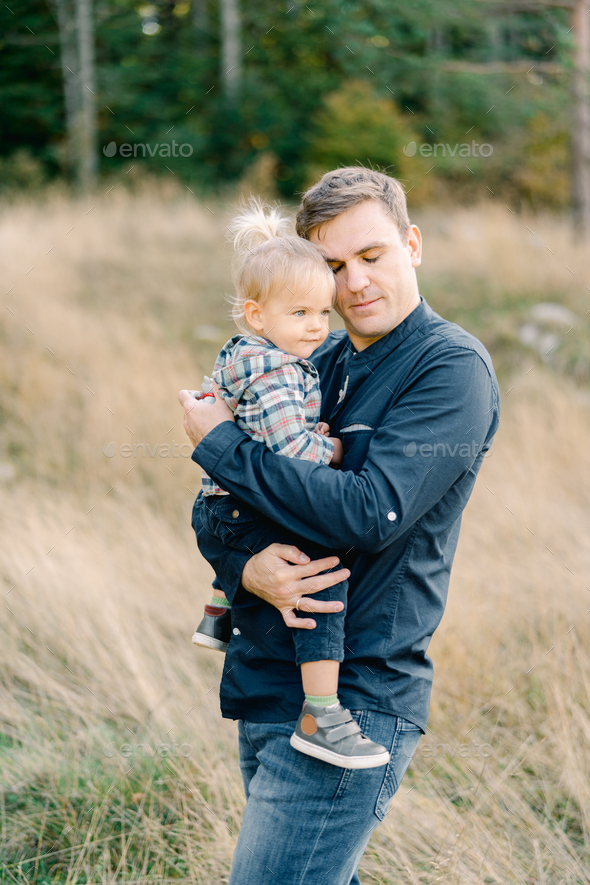 Dad hugs a little girl in his arms leaning his forehead against her ...