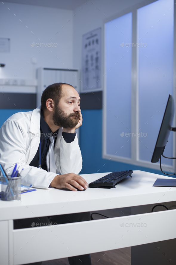 Tired doctor reviewing medical files Stock Photo by DC_Studio | PhotoDune
