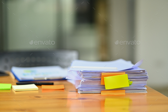Pile of documents with colorful sticky notes on wooden office desk ...