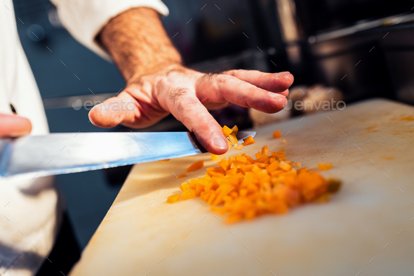 Close up of chef hands cooking in a commercial kitchen choping cartot ...