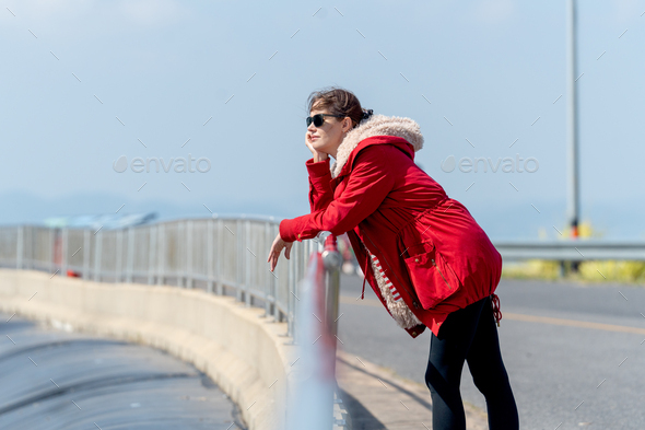 Side view of Caucasian woman with red coat and sun glasses lean to ...