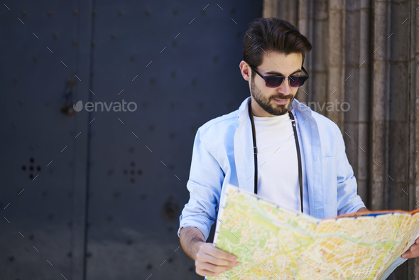 Handsome ethnic man exploring paper map near old building Stock Photo ...