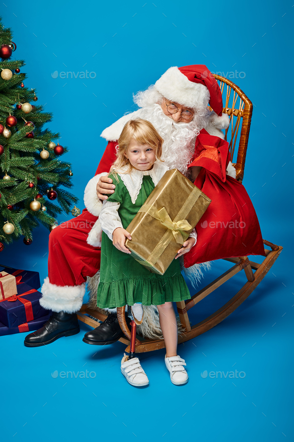 Santa Claus giving present to happy girl with prosthetic leg next to ...