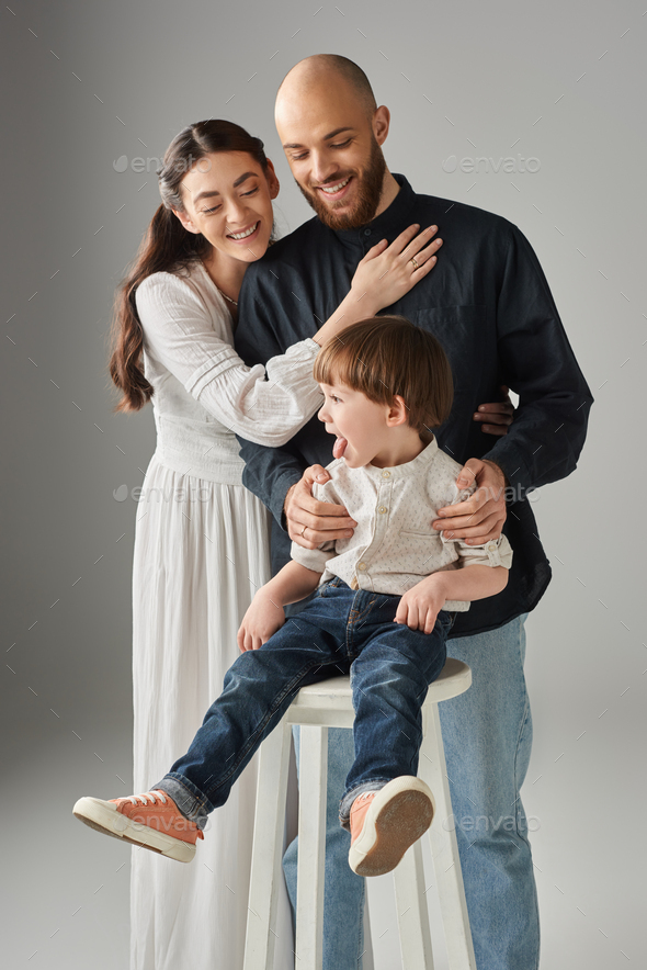 cheerful modern parents hugging with their sitting on tall chair in ...