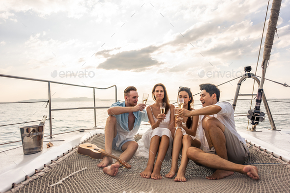 Group of diverse friend sit on deck of yacht while yachting together ...