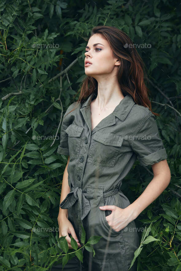 Woman in the forest The hand in the pocket of the overalls looks aside ...