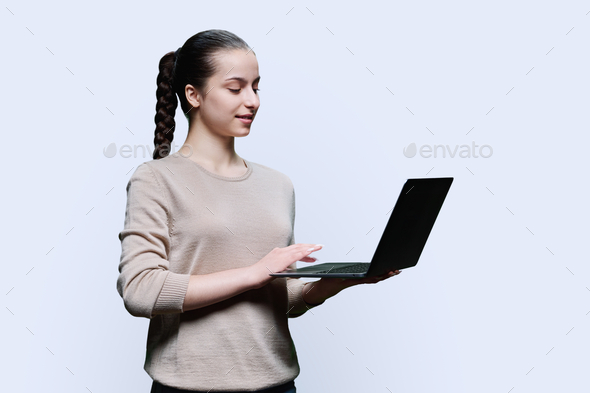 Teen girl high school student using laptop looking at computer on white ...