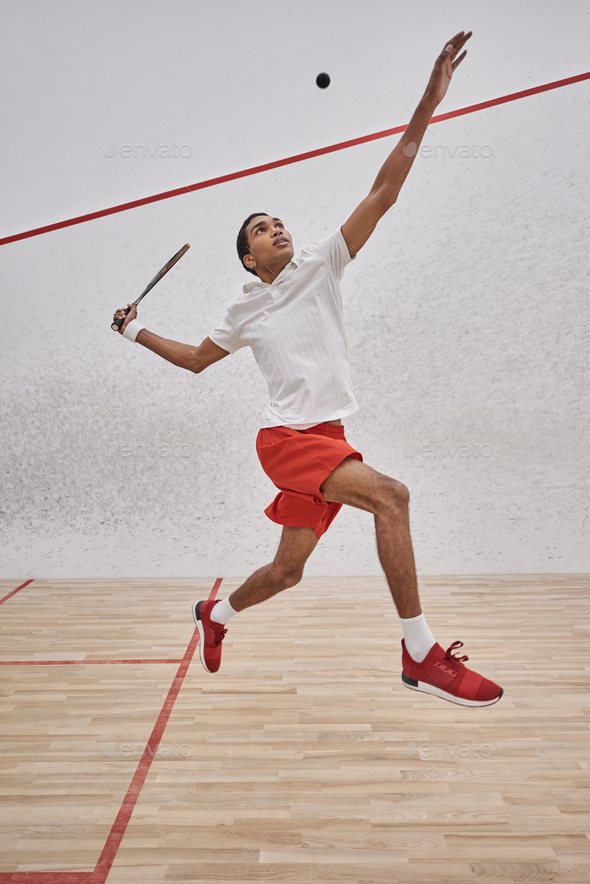 motion, focused african american player with racquet jumping and ...