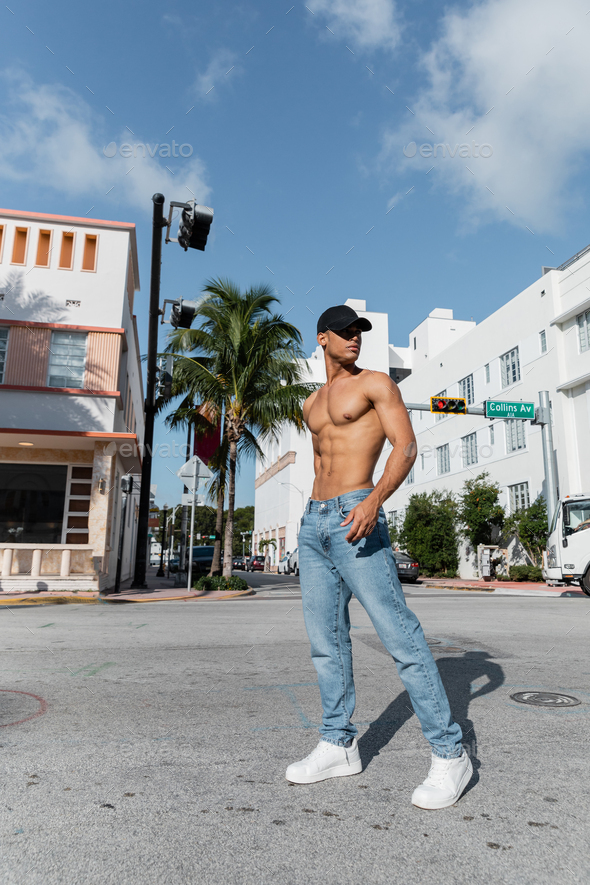 cuban man with athletic body in baseball cap and blue jeans on street ...