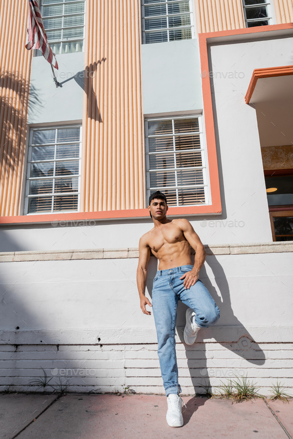 Sexy cuban man with athletic body in baseball cap and jeans standing on ...