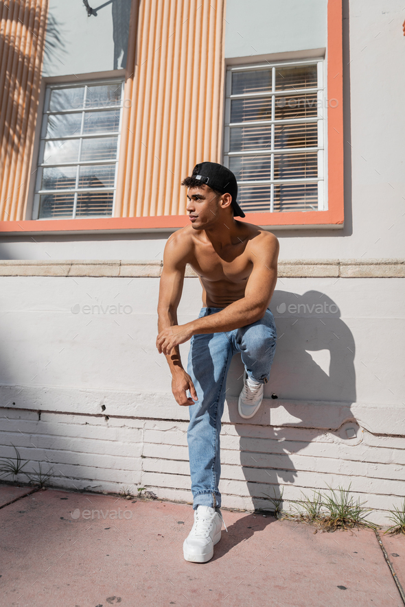 cuban man with muscular body in baseball cap and jeans standing on ...
