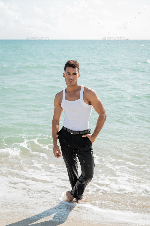 handsome muscular young Cuban man standing in ocean water in Miami ...