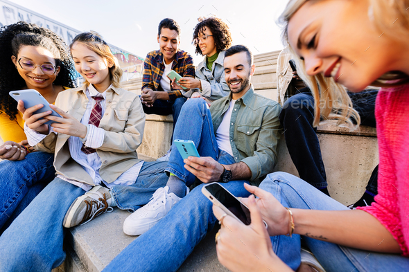 Addicted young people using mobile phones sitting together outdoors ...