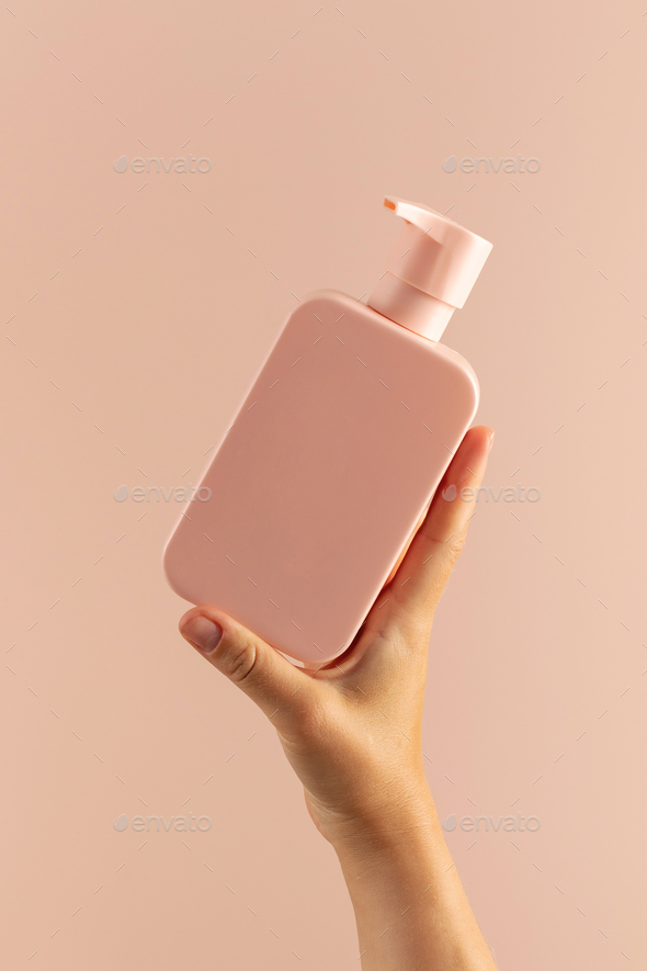A mock-up of a pink dispenser with cosmetics in a woman's hand. Stock ...