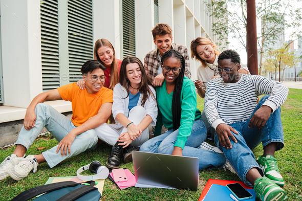 Portrait of multiracial college students using a laptop computer while ...