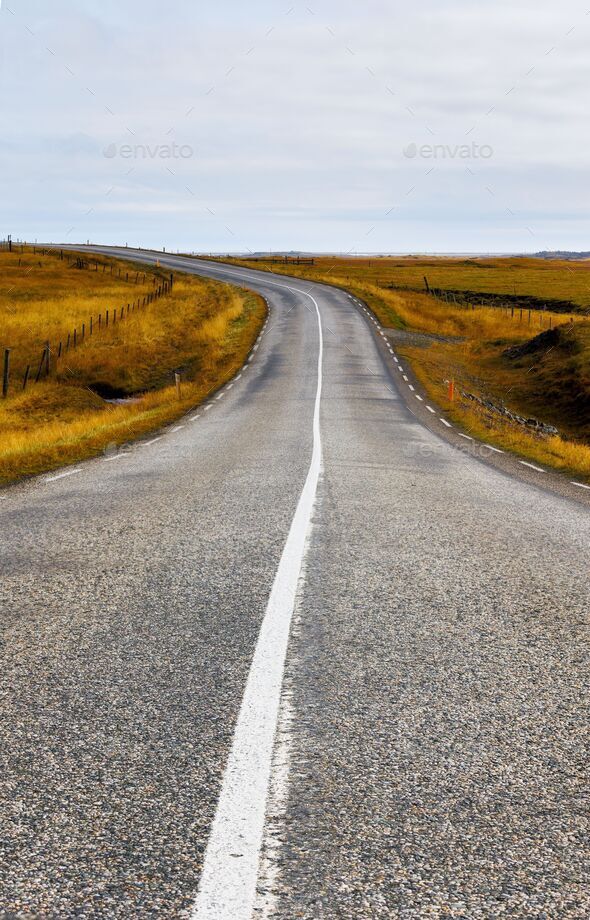 Scenic country road stretches across the horizon of a vast, open field ...