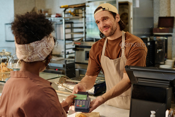 Smiling Cashier Receiving Contactless Payment from Buyer Stock Photo by ...