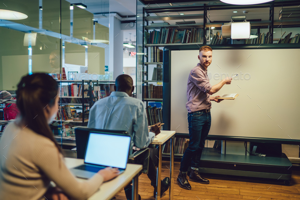 Confident student doing presentation for multiethnic classmates beside ...