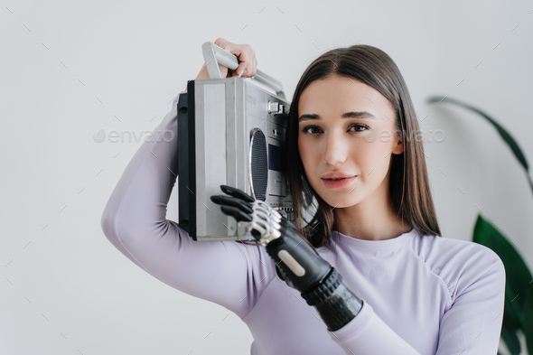 Adorable girl with cyber hand holds old fashion audio layer looks at ...