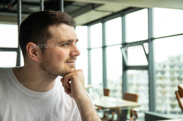 Attractive young guy looking out the window in the office Stock Photo ...