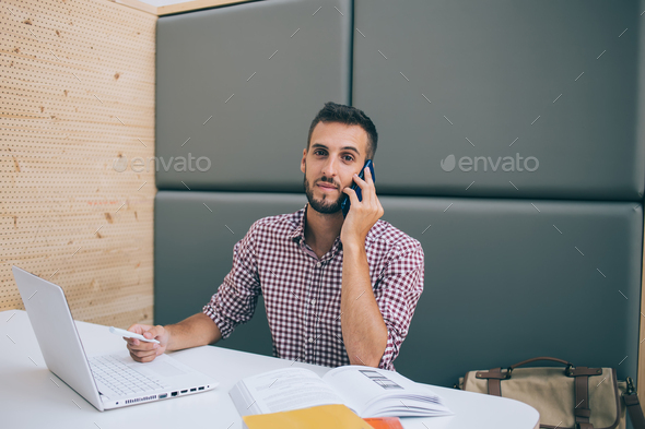 Handsome guy calling partner during creating startup at workplace Stock ...