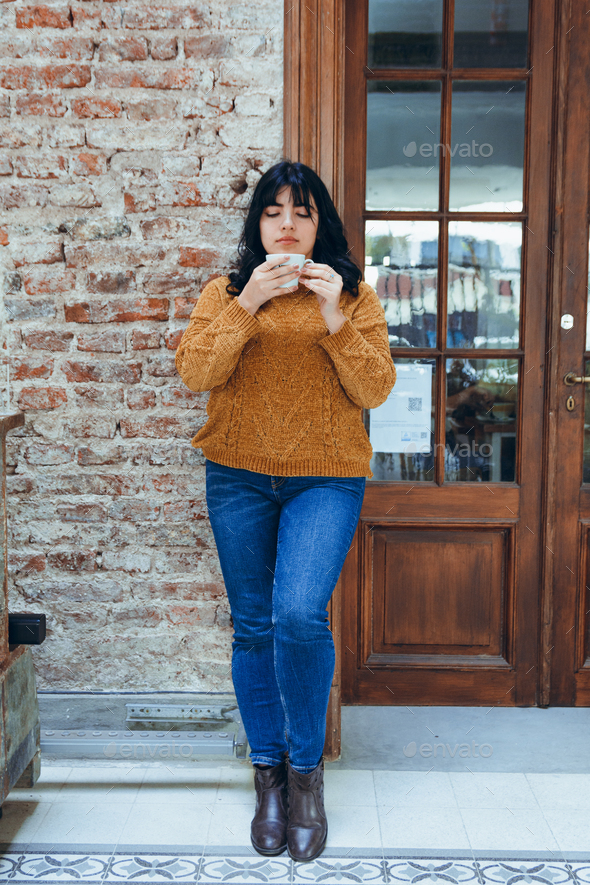 vertical image latin young woman standing drinking coffee in coffee ...
